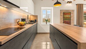 Cozinha moderna com armários escuros, bancada de madeira e luminária pendente.