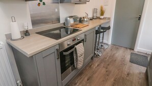 Cozinha moderna com fogão de aço inoxidável, forno embutido, torradeira e chaleira no balcão.