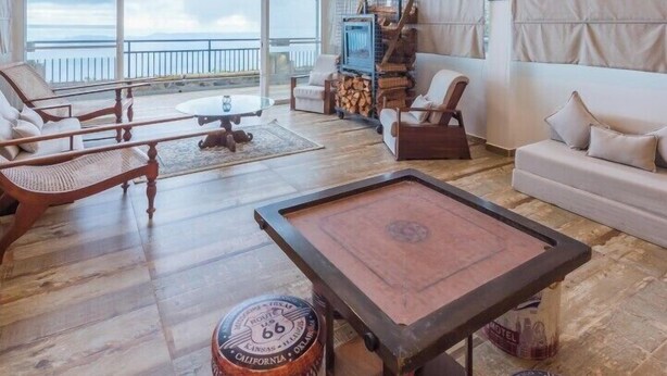 Uma sala de estar espaçosa com mesa de bilhar, assentos confortáveis e grandes janelas com vista para o mar.