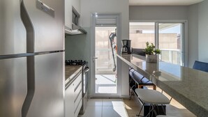 Uma cozinha moderna com eletrodomésticos de aço inoxidável, um espaço de jantar com um banco e vista para o exterior.