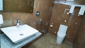 Casa de banho com lavatório branco, espelho, sanita e área de duche.