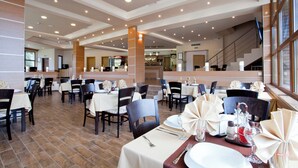 Um restaurante espaçoso com várias mesas de jantar preparadas para os hóspedes, com design de interiores moderno e bastante espaço para sentar.