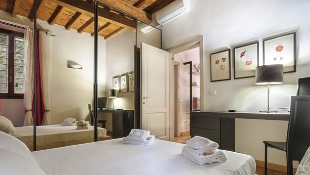 Quarto de hotel com uma cama grande, uma escrivaninha com cadeira, espelho e obras de arte na parede.