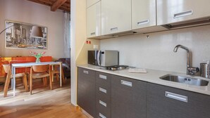 Uma cozinha moderna com micro-ondas embutido, pia de aço inoxidável e mesa de jantar de madeira com cadeiras.