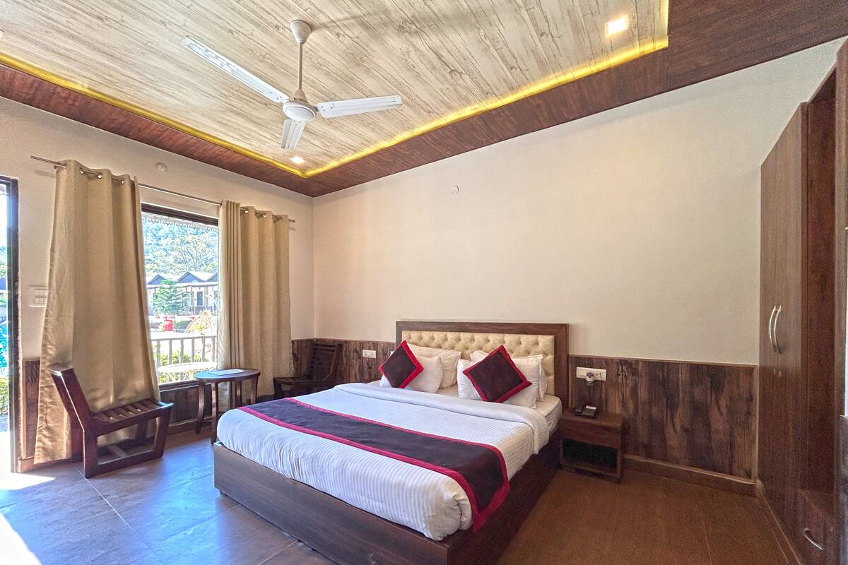 Um quarto espaçoso com uma cama grande, um ventilador de teto e vista para o exterior pela janela.