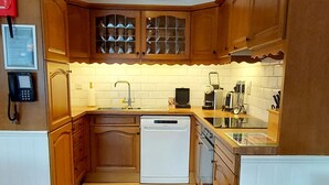 Uma cozinha compacta com armários de madeira, lava-louças embutida e painel de azulejos.