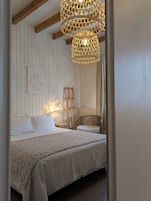 Quarto com cama, abajures, escada e obra de arte na parede.