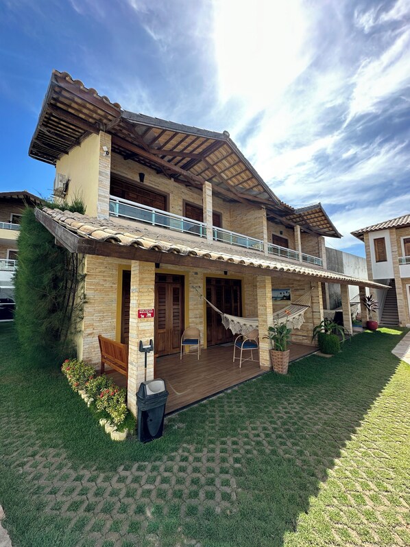 Uma casa de dois andares com varanda, deck de madeira e gramado.