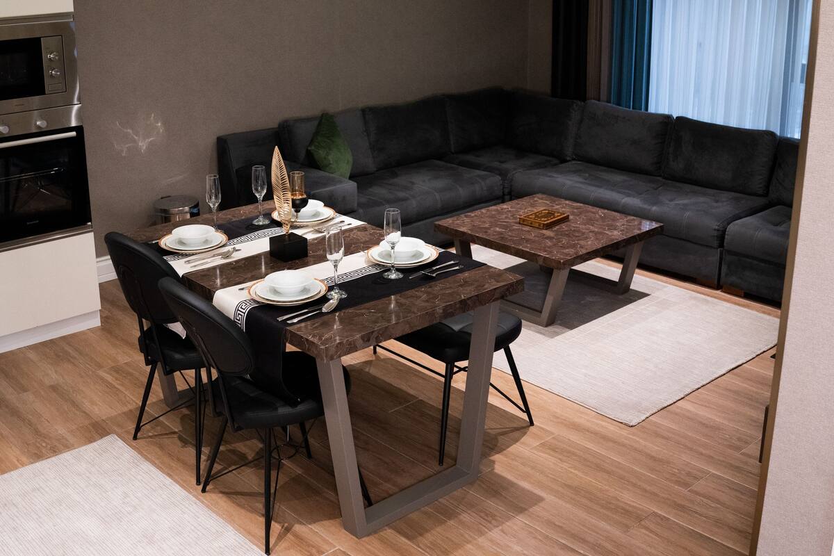 Uma sala de estar moderna com área de jantar, sofá e cozinha equipada.