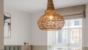 Quarto moderno com uma cama grande, luminária pendente de vime, abajur e vista da cidade através de grandes janelas.