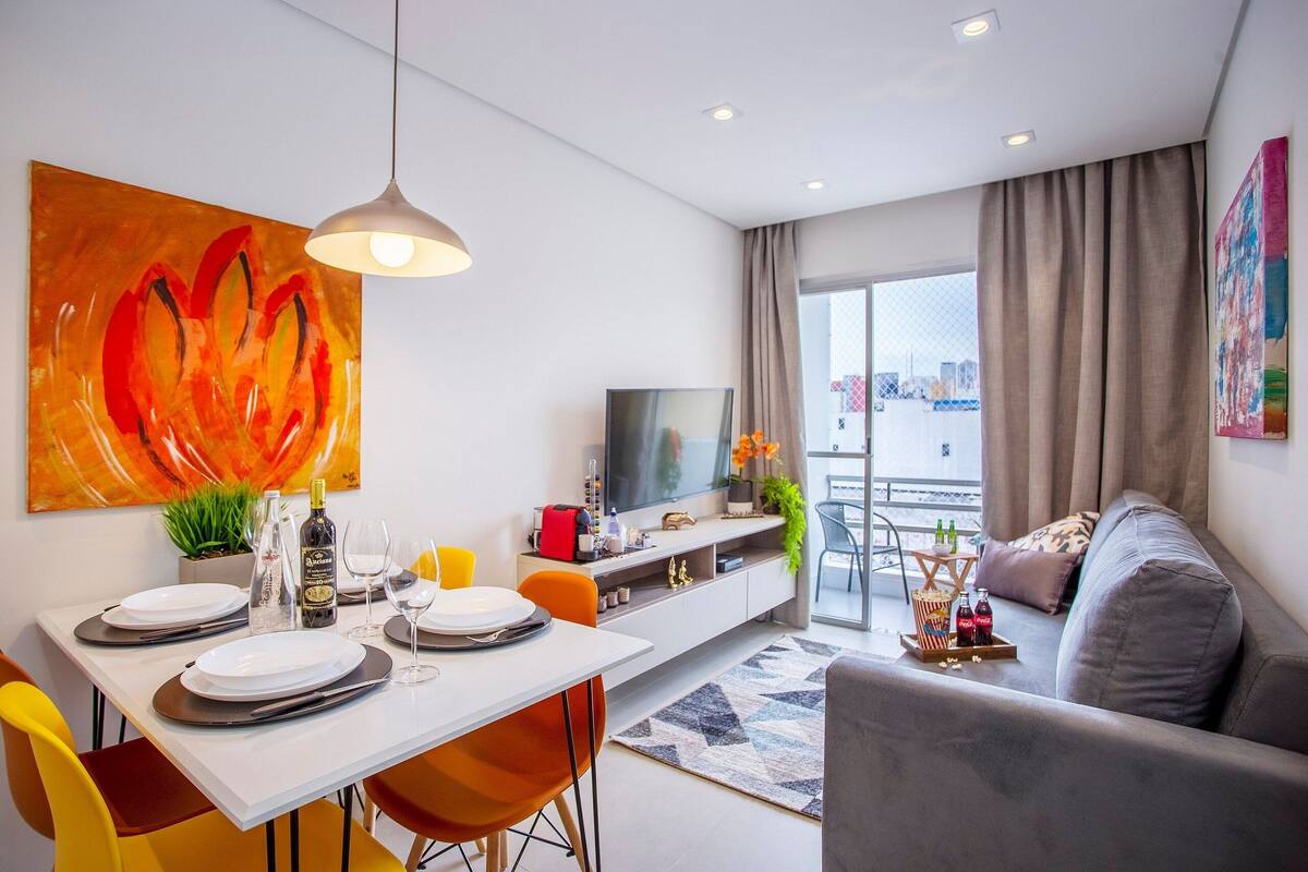 Uma sala de estar moderna com área de jantar, sofá e televisão.