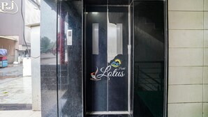 Entrada de hotel com uma porta preta exibindo o logotipo da Lotus e um desenho de montanha.