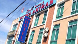 Um hotel com uma placa indicando 'WISMA AKIRAN' e uma placa grande com a palavra 'HOTEL'.