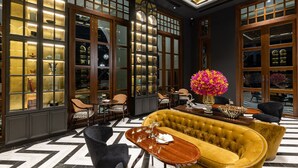 Um hall de entrada luxuoso com um sofá grande, área de estar e um vaso decorativo.
