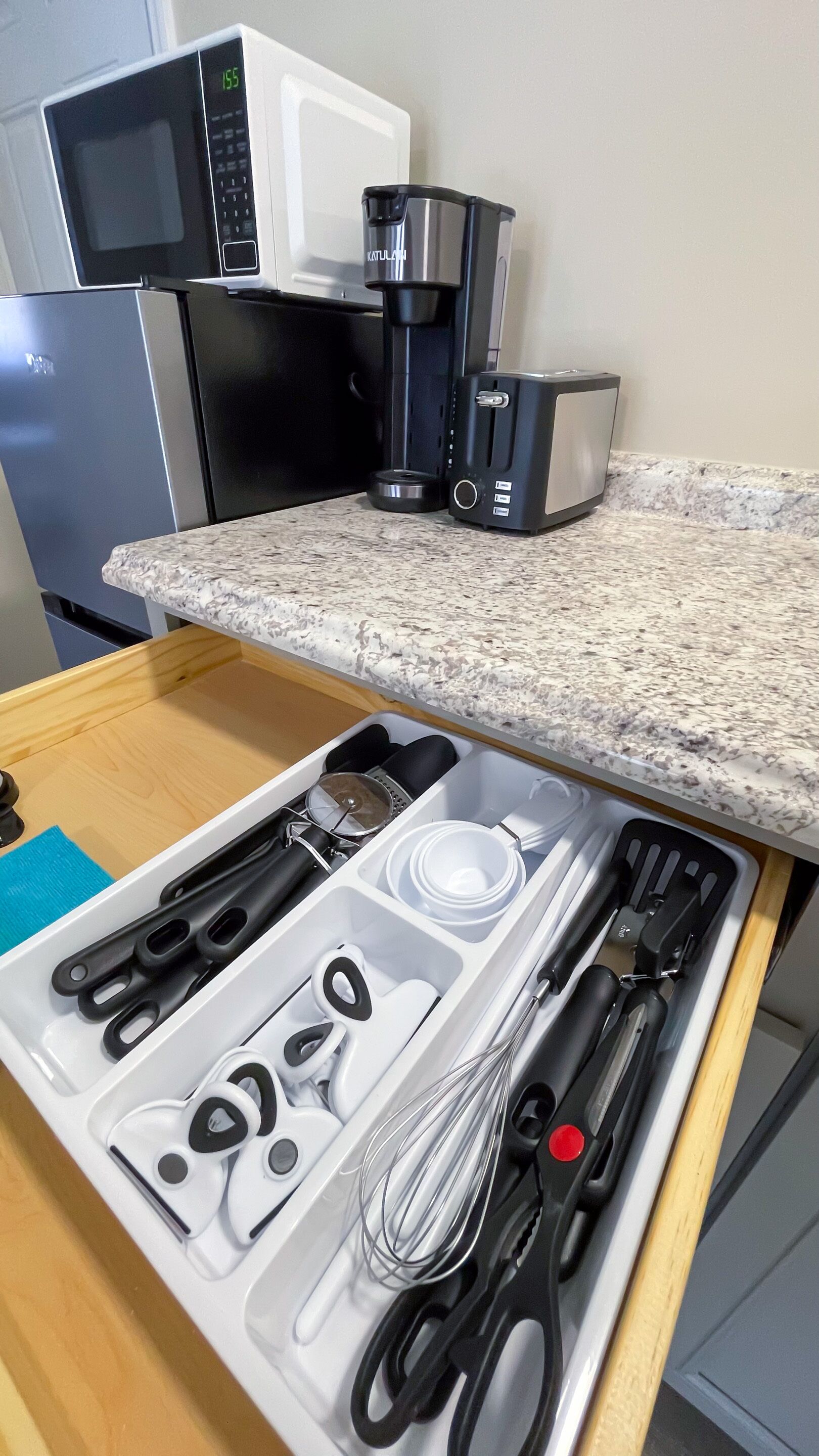 Cozinha equipada com micro-ondas, máquina de café, torradeira e uma gaveta com utensílios de cozinha.