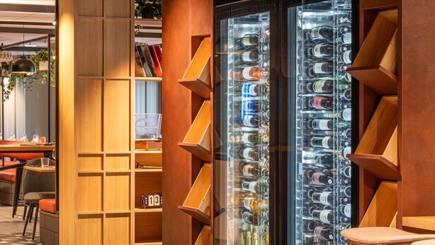 Um interior moderno com um refrigerador de vinhos, estantes de madeira e um piso estampado.