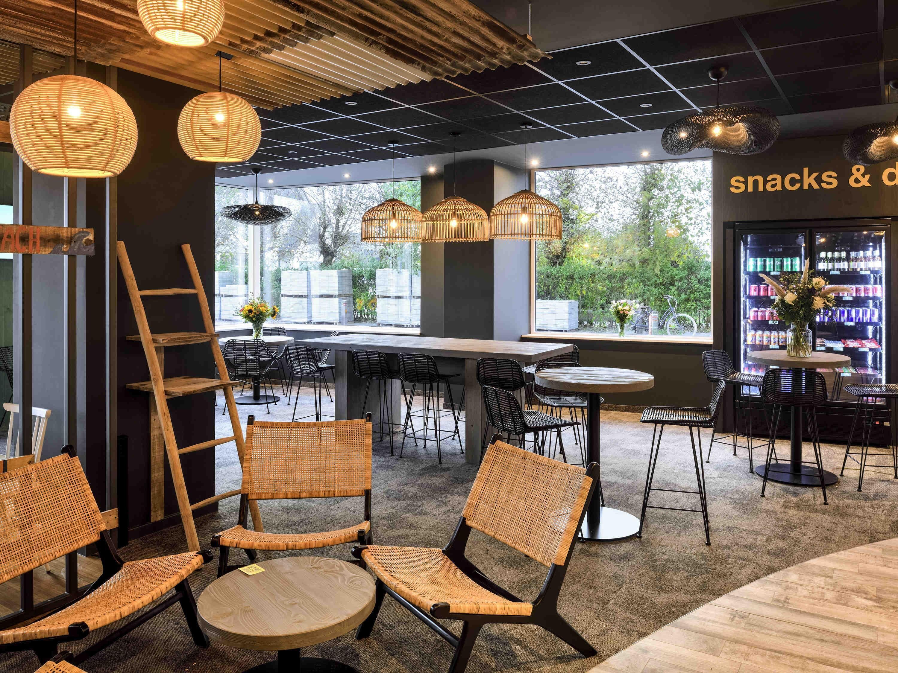 Interior moderno de café com móveis de vime, área de bar e exposição de lanches.