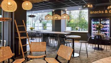 Interior moderno de café com móveis de vime, área de bar e exposição de lanches.