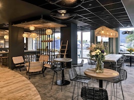 Interior moderno de café com móveis de vime, mesas redondas e luminárias de vime suspensas.