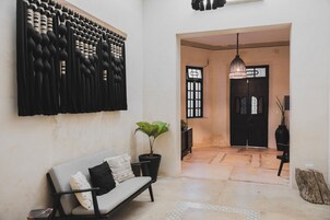 Um interior moderno com um sofá, uma planta em vaso e um painel decorativo na parede.