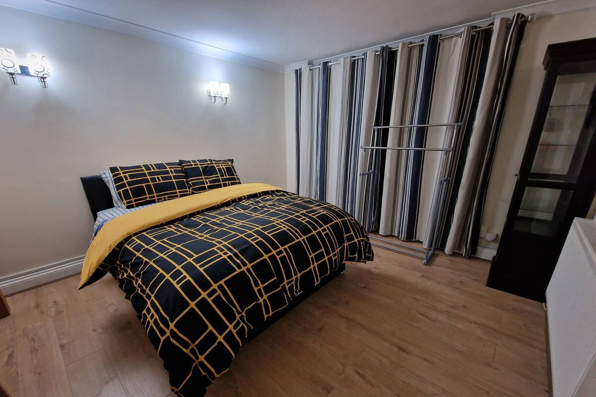 Quarto com cama, cortinas e radiador.