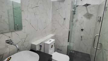 Um banheiro moderno com uma pia grande e branca, um vaso sanitário e área de chuveiro com paredes de vidro.
