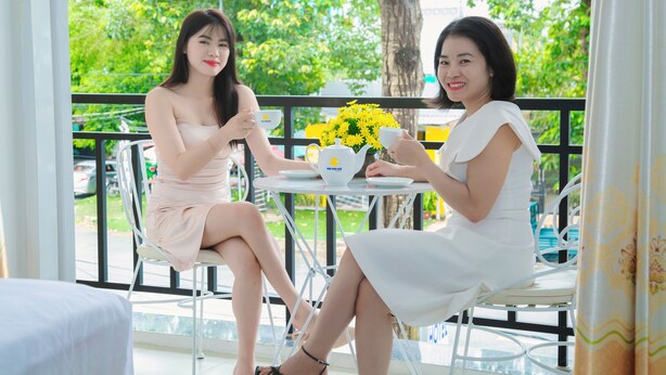 Duas mulheres sentadas numa mesa ao ar livre, com vista para árvores e vegetação.