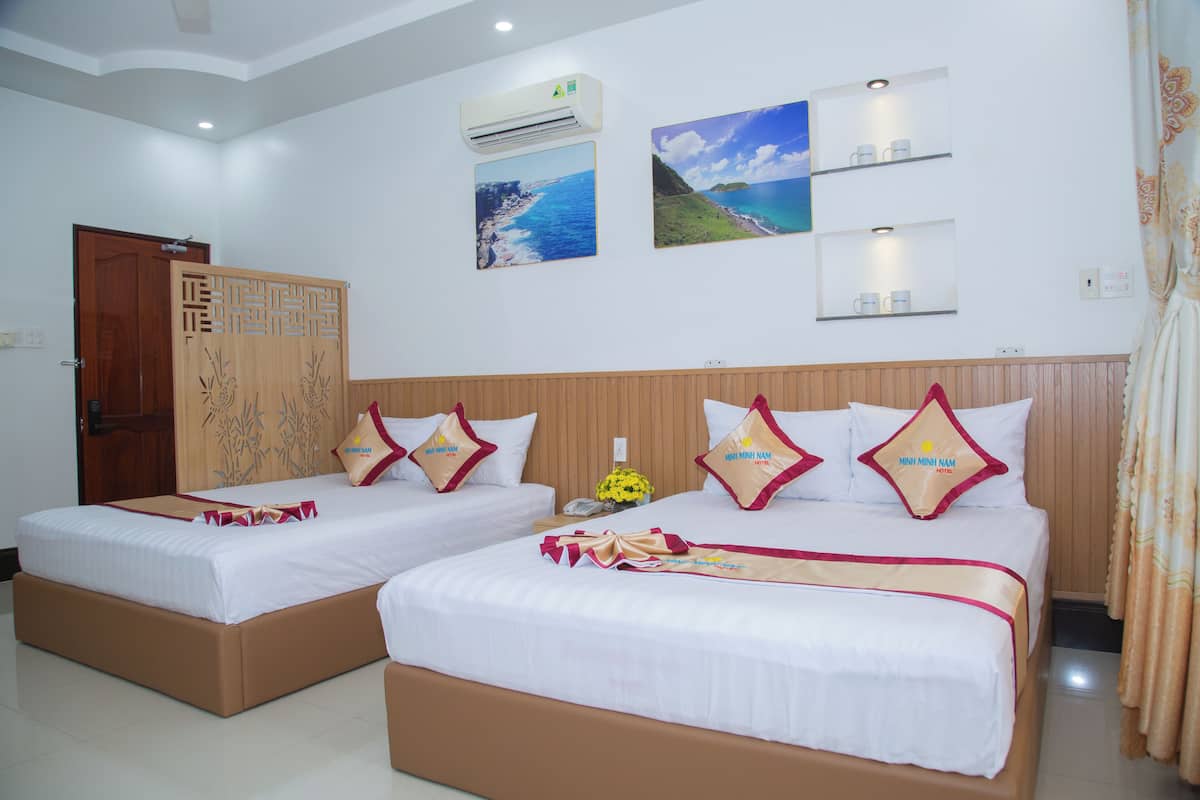 Quarto de hotel com duas camas, um guarda-roupa de madeira, ar condicionado fixado na parede e quadros com paisagens.