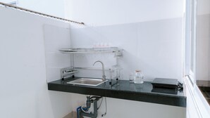 Cozinha pequena e moderna com bancada preta, pia de aço inoxidável e lava-louças embutida.