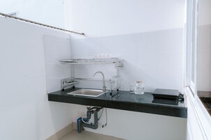Cozinha pequena e moderna com bancada preta, pia de aço inoxidável e lava-louças embutida.