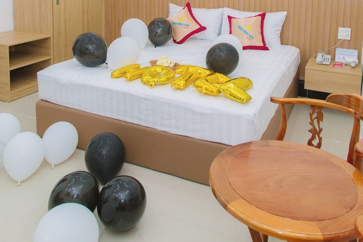 Um quarto com cama, balões e um enfeite na parede.