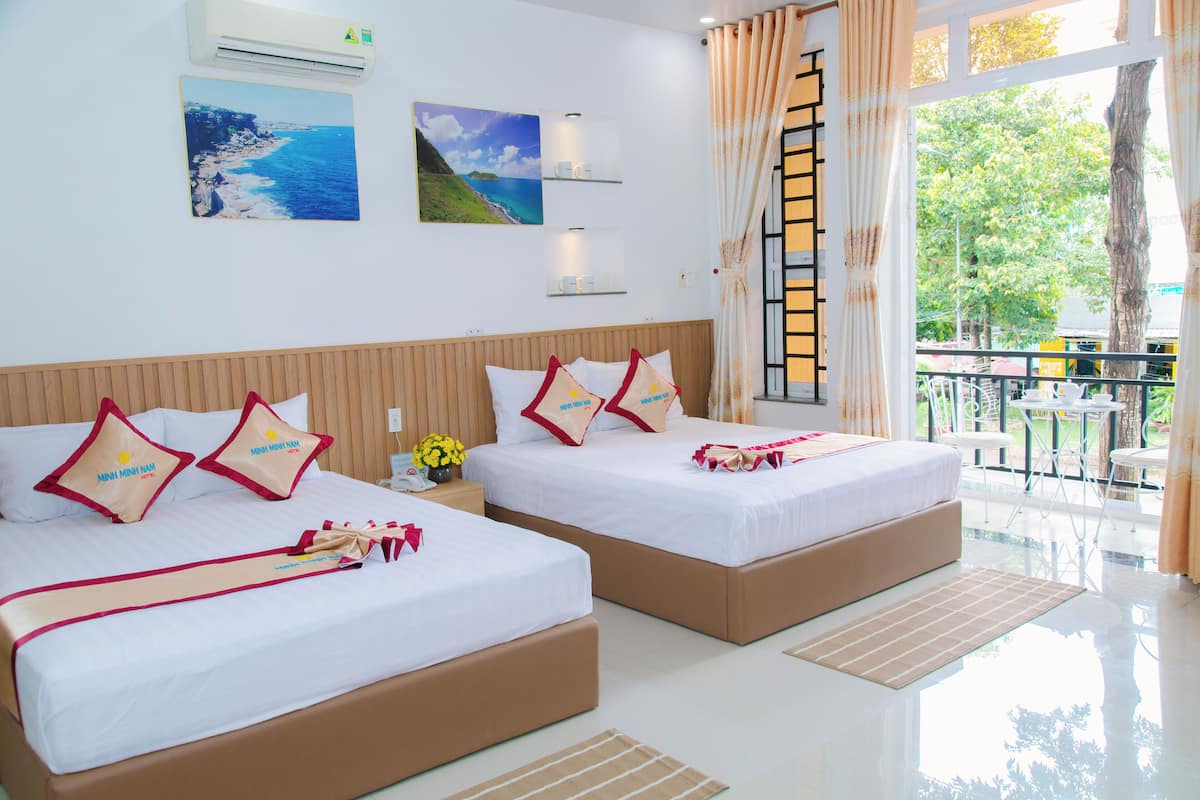 Quarto de hotel com duas camas, varanda e vista para o mar.