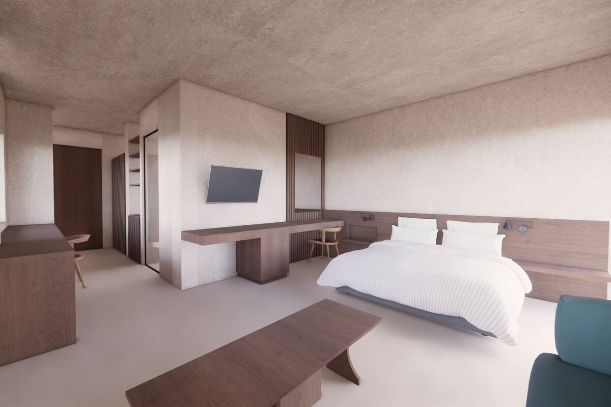 Quarto de hotel moderno com uma cama grande, uma escrivaninha, uma cadeira e um banco.