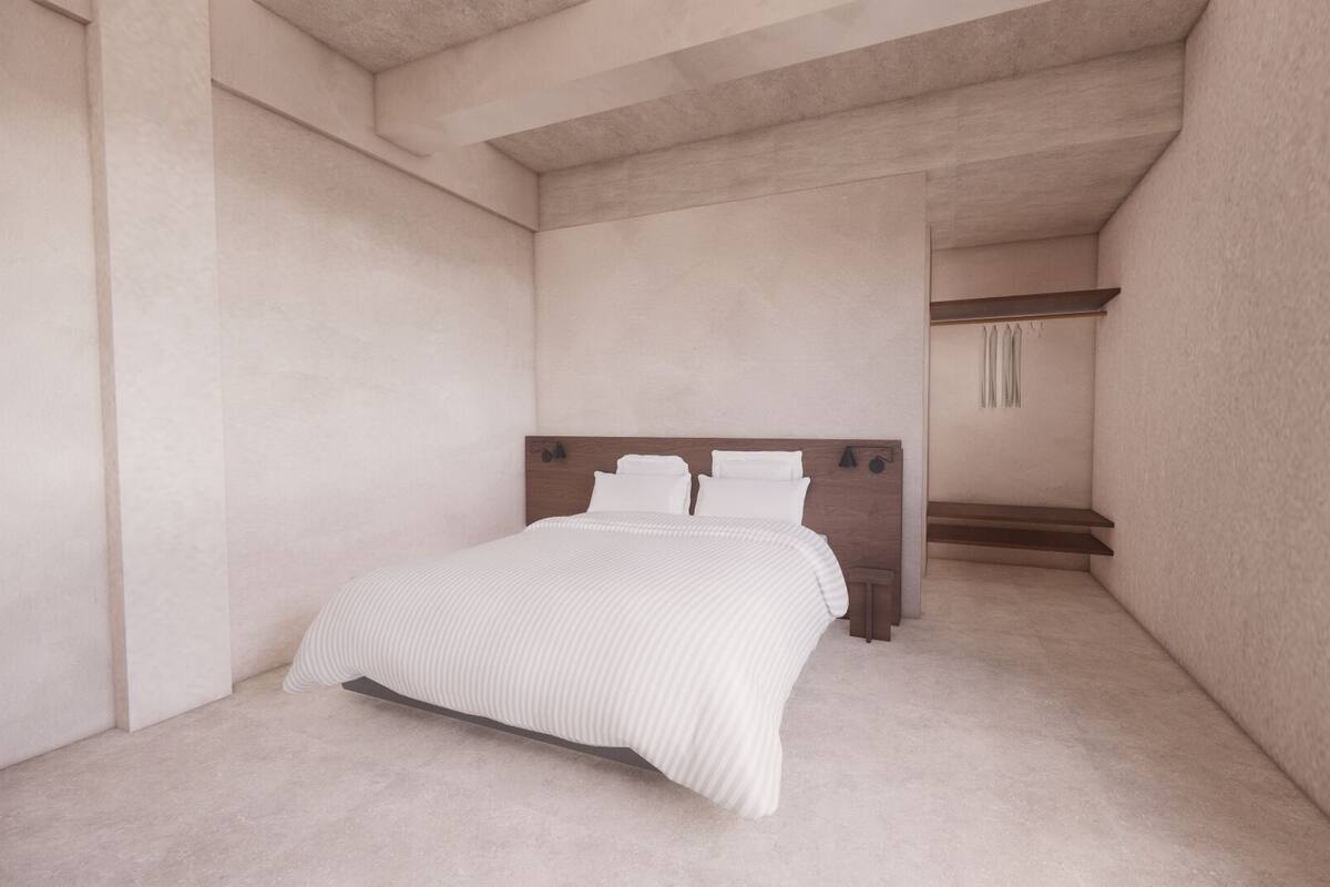 Quarto minimalista com uma cama, cabeceira de madeira e piso coberto de carpete.