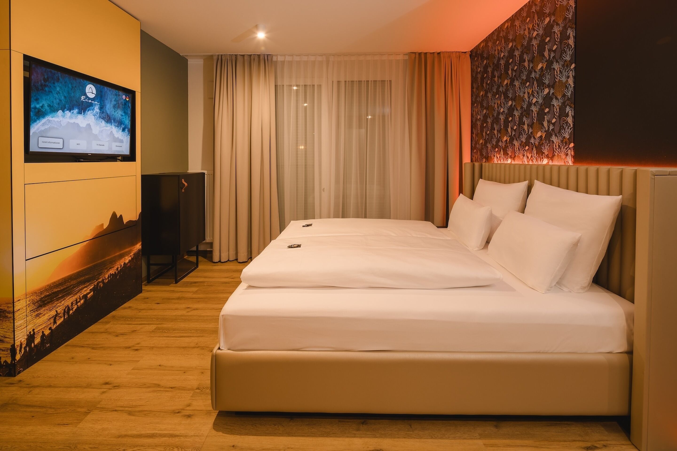 Quarto de hotel com uma cama grande, televisão de tela plana fixada na parede e um painel decorativo.