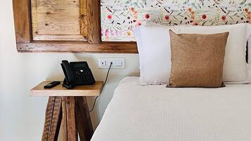 Quarto com cabeceira de madeira, mesa de cabeceira com telefone e cama com almofadas.