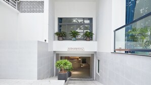 Uma área de recepção com design moderno, destacando um balcão de atendimento, plantas em vasos e uma vista desobstruída do interior.