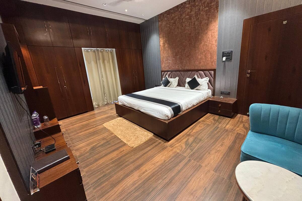 Quarto moderno com uma cama grande, uma poltrona azul e piso de madeira.