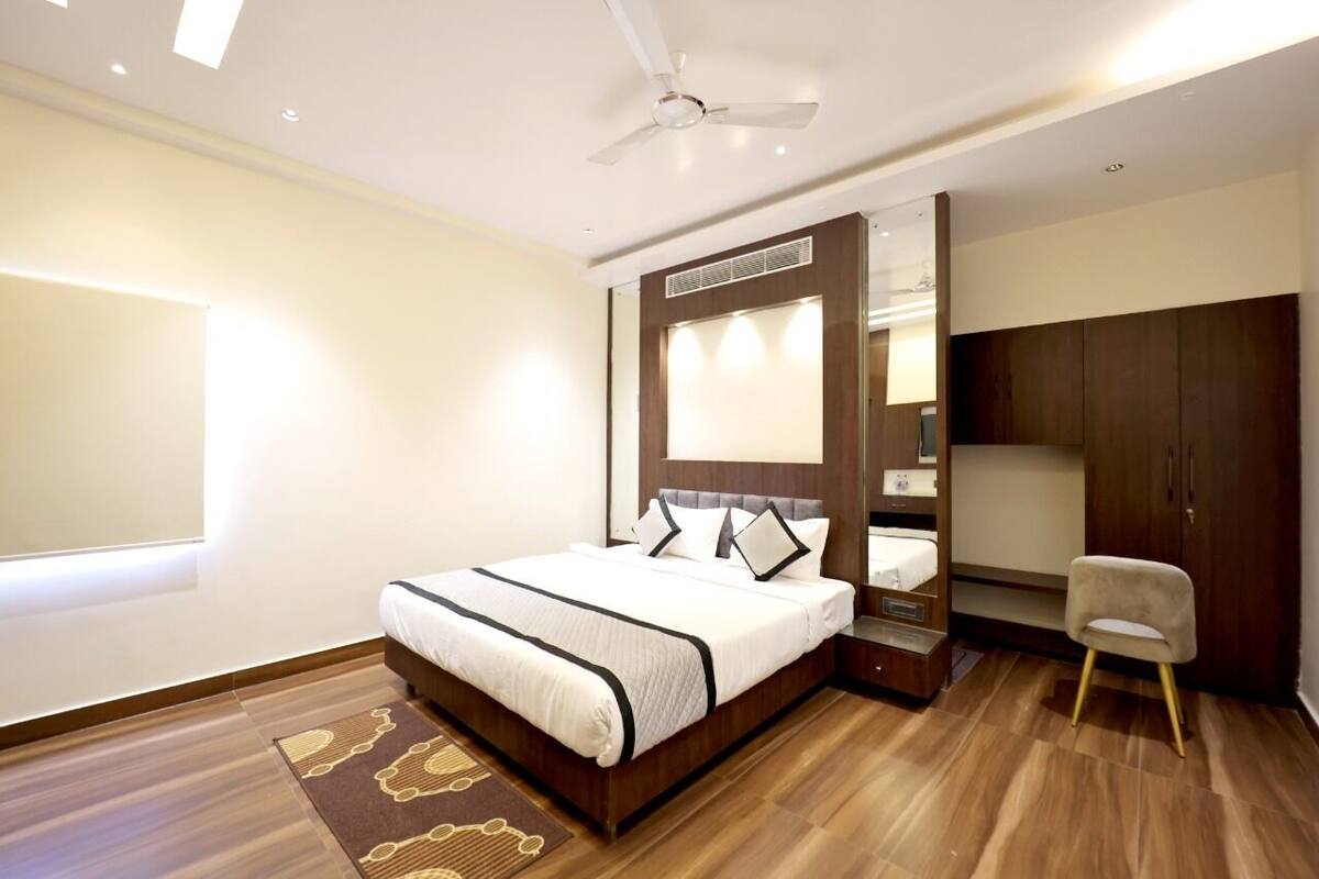 Quarto moderno com cama grande, ventilador de teto, guarda-roupa e mesa de cabeceira.