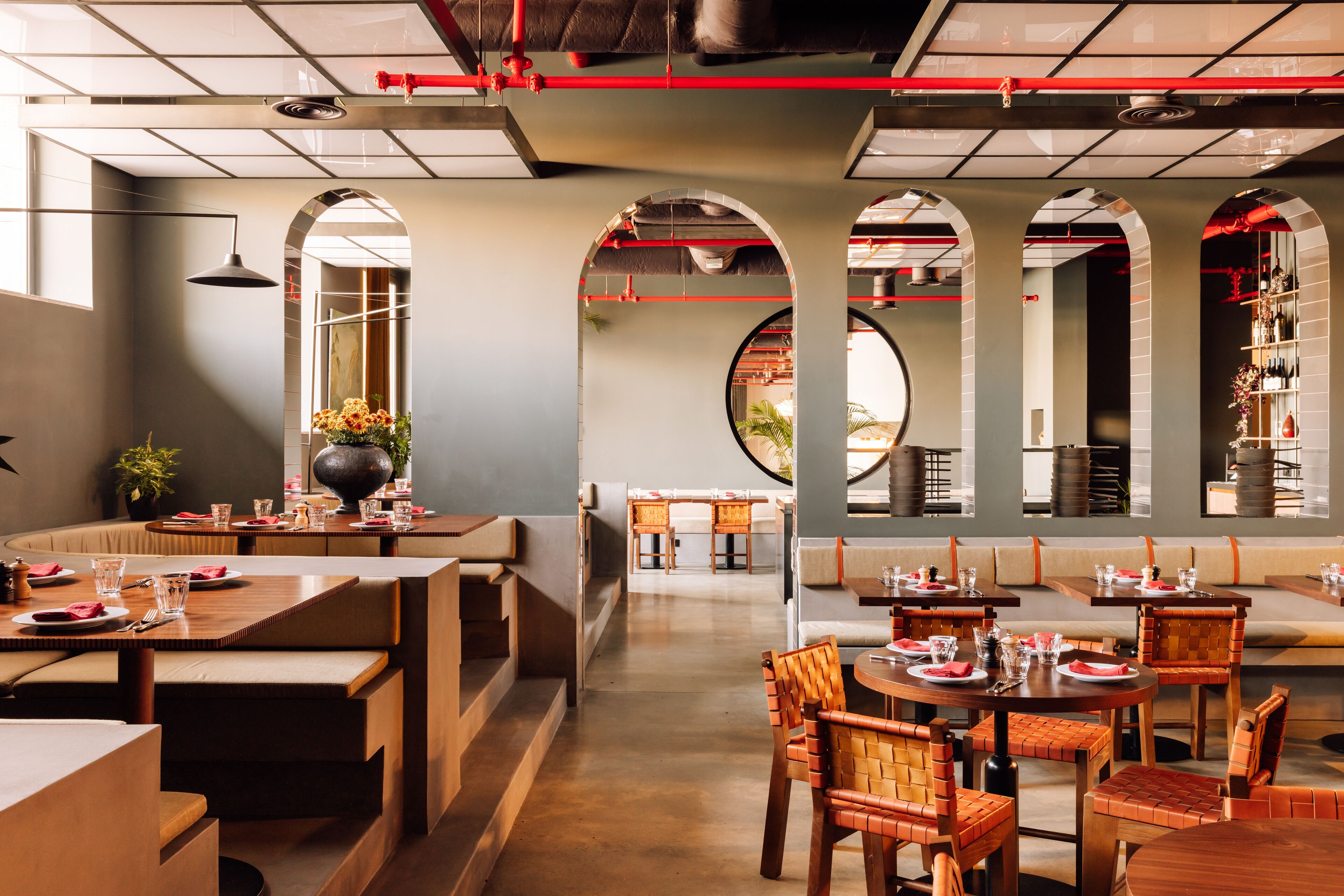 Um restaurante com mesas altas, cabines, tetos em arco e design de interiores moderno.