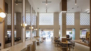 Interior moderno com balcão extenso, área de estar e grandes janelas com painéis estampados.