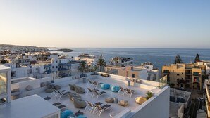 Terraço no telhado com área de estar ao ar livre, com vista para a paisagem costeira urbana.