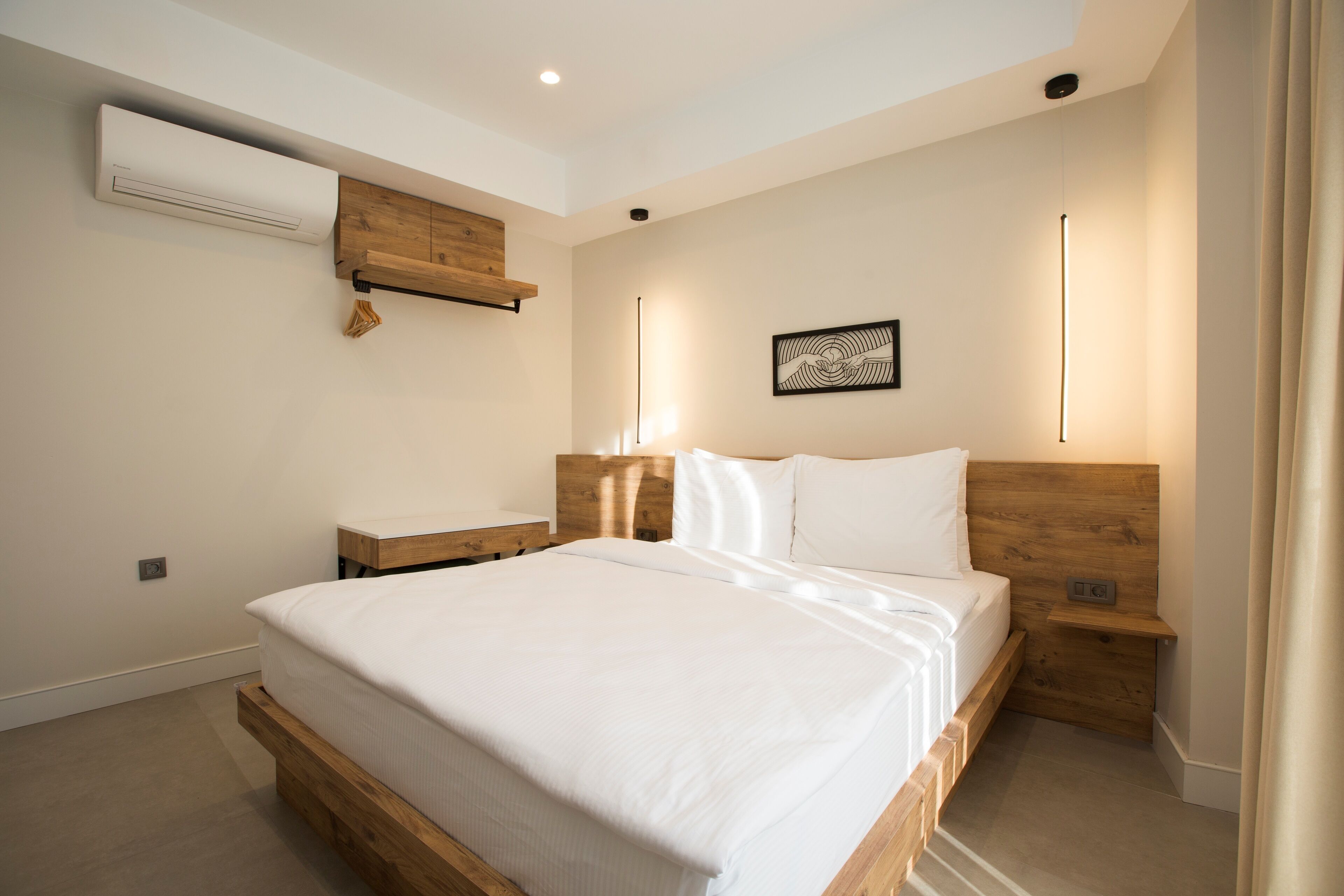 Quarto com estrutura de cama de madeira, mesa de cabeceira, ar-condicionado fixado na parede e luminária pendente.