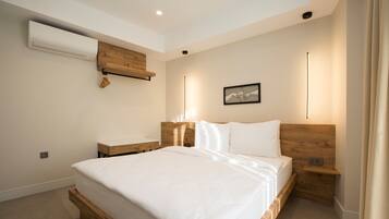 Quarto com estrutura de cama de madeira, mesa de cabeceira, ar-condicionado fixado na parede e luminária pendente.