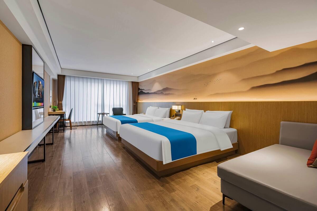 Quarto de hotel com duas camas, uma mesa e uma televisão.