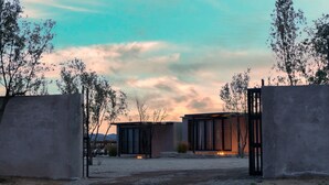 Um edifício moderno com design minimalista, apresentando duas estruturas distintas com grandes janelas e chão de cascalho.