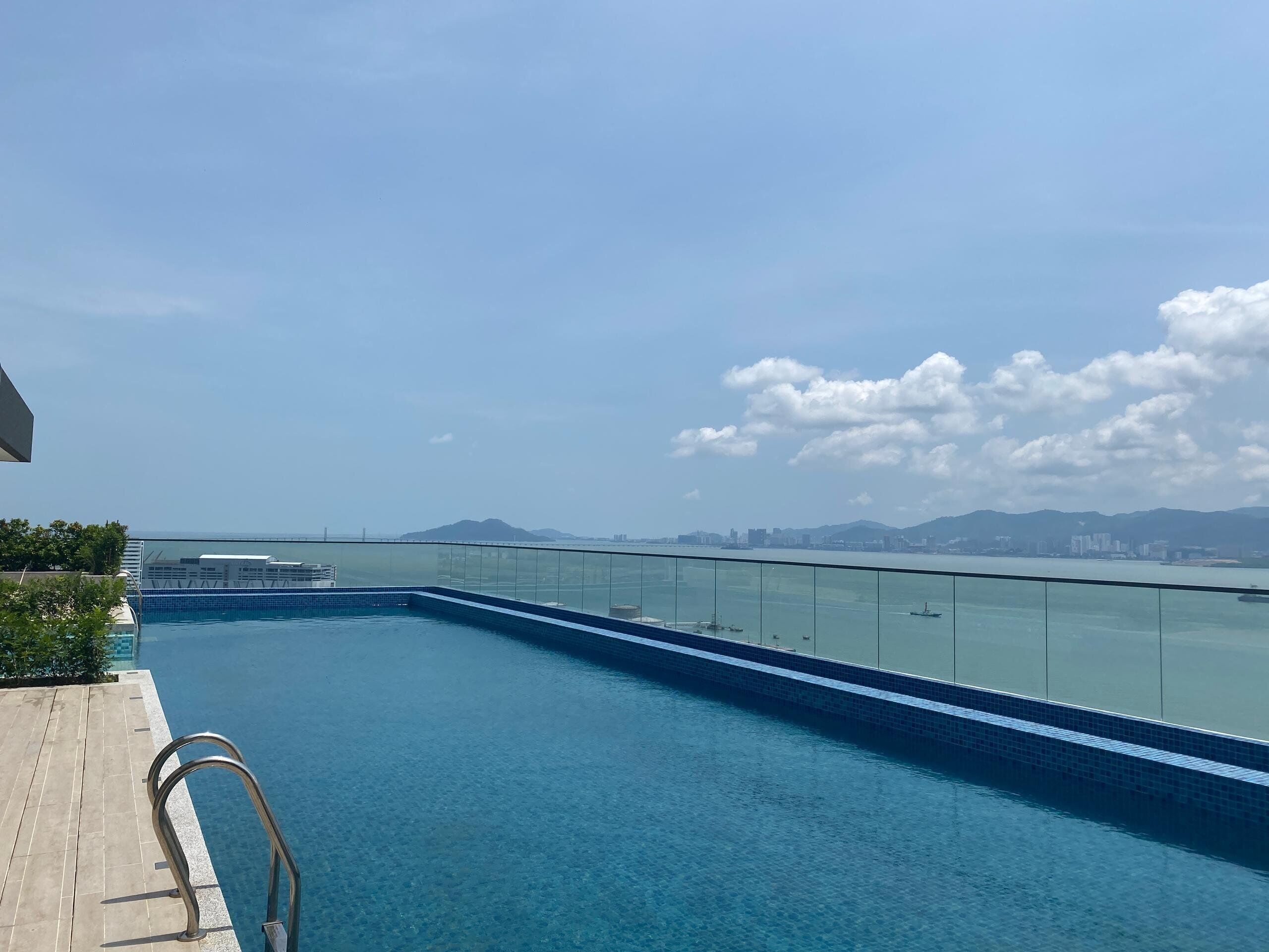 Piscina com barreira de vidro e vista para o horizonte urbano sobre a água.