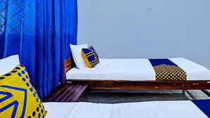 Quarto com duas camas, cortinas azuis e almofadas estampadas.