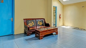 Um quarto com uma porta azul marcada com o número 2, um banco de madeira com desenhos elaborados e um piso de azulejos.