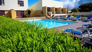Um hotel moderno com piscina, espreguiçadeiras e um jardim bem cuidado.